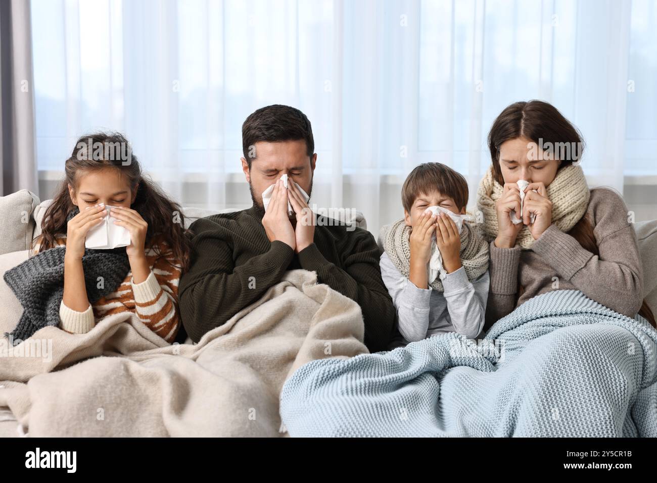 Cold symptom. Family suffering from fever on sofa at home Stock Photo ...