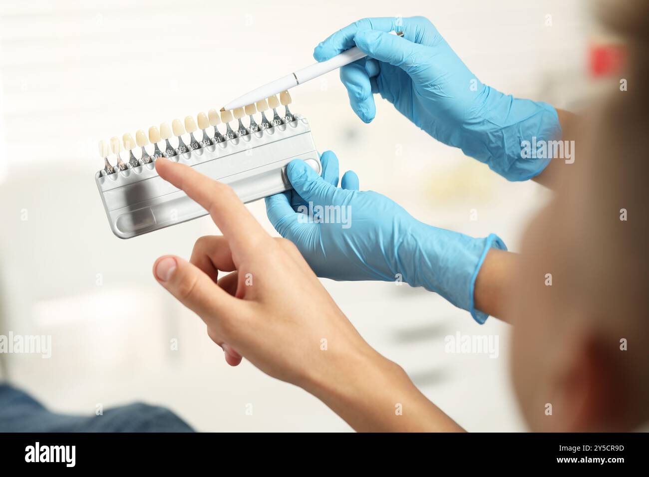 Doctor and patient choosing shade on teeth color palette in clinic ...