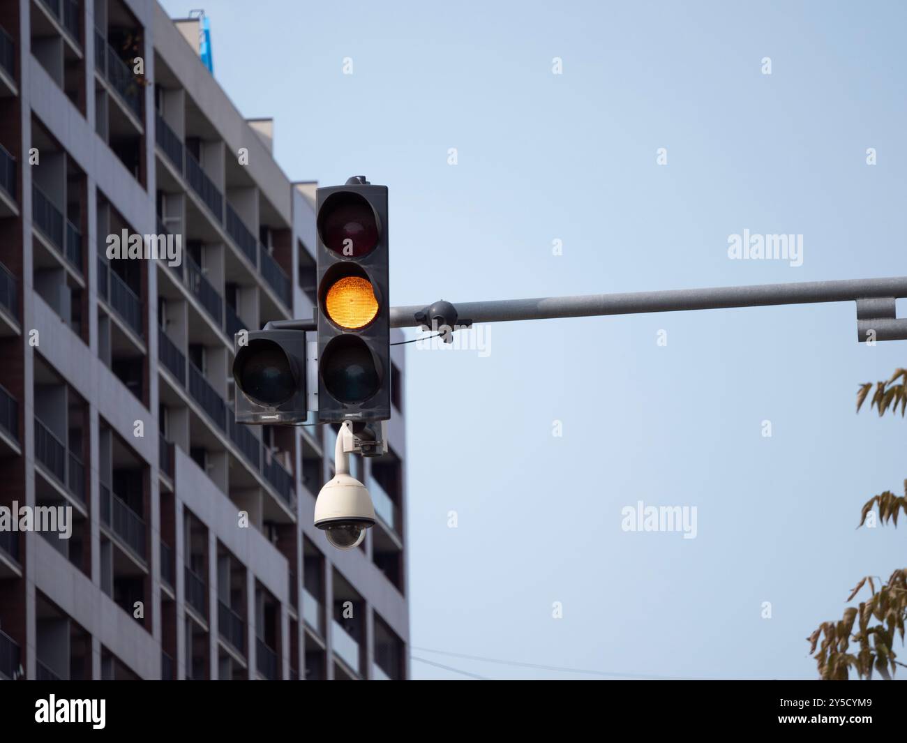 A traffic light with a yellow light is on a street in front of a ...
