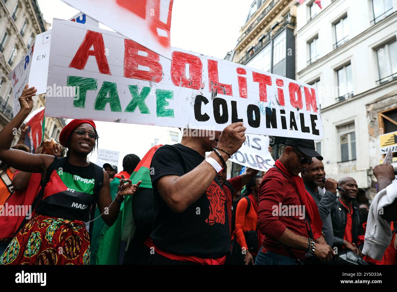 A protester holding a sign with the message "abolition of the colonial ...