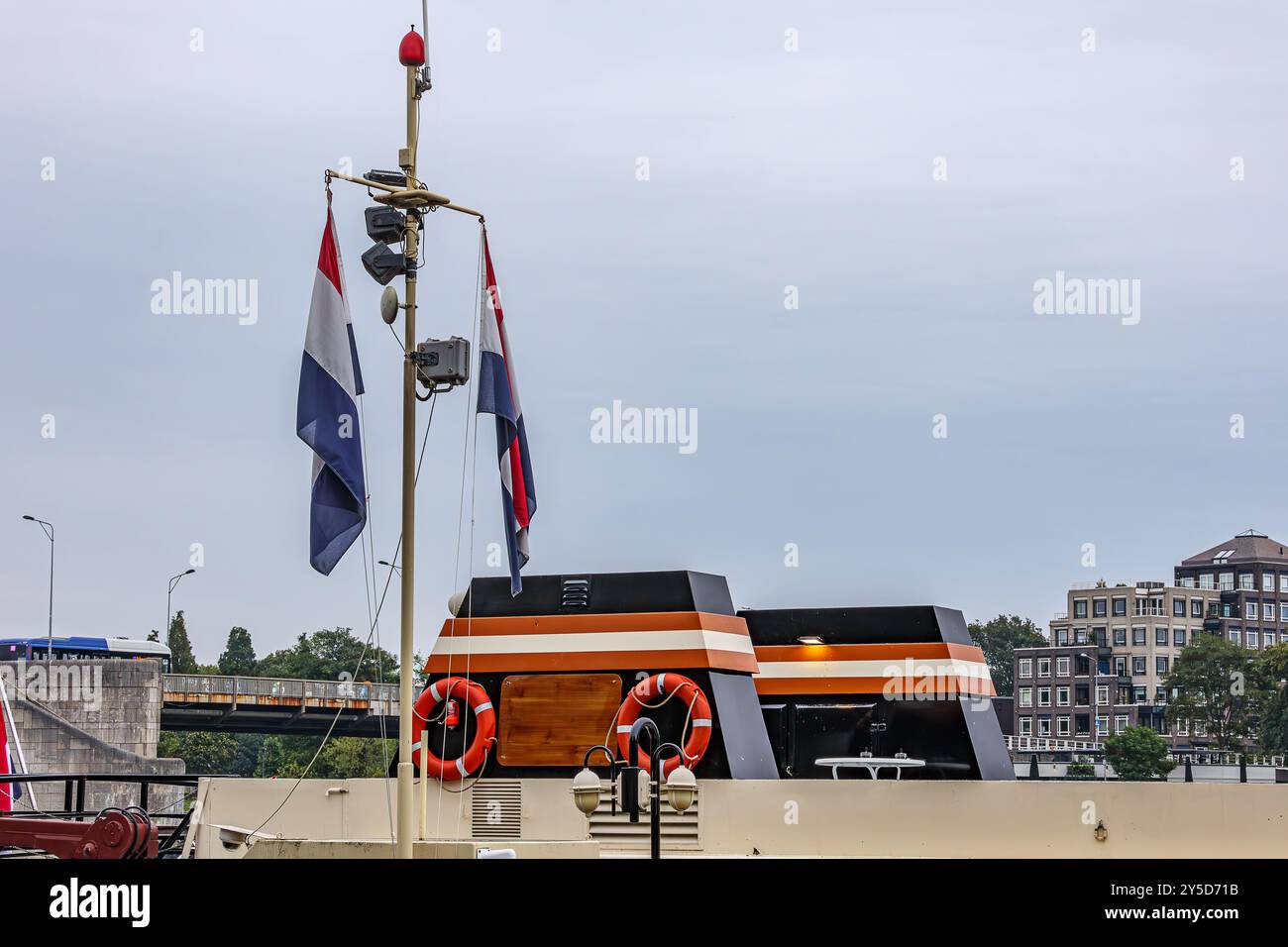Dutch flags on ship flagpole against grey sky, flybridge roof, two ...