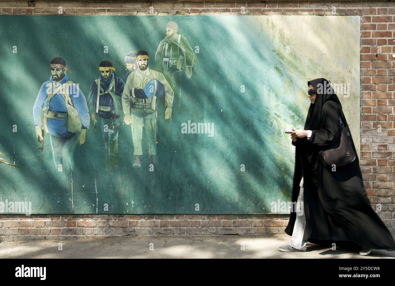 Black veil wearing muslim woman walking past martyr mural outside old ...