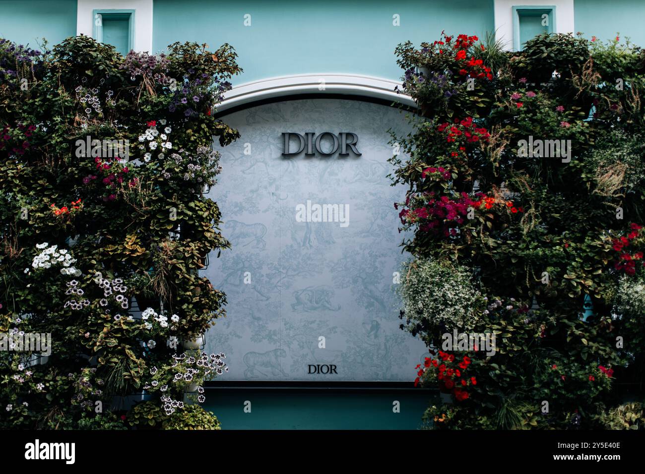 Beautiful turquoise facade of luxury boutique Dior with fresh flowers ...