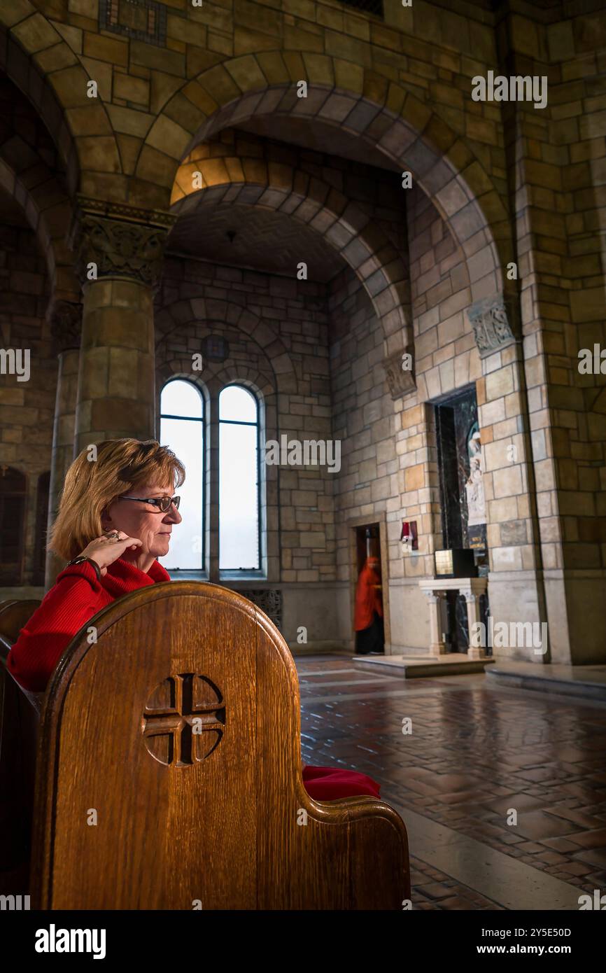 Woman sitting in church looking at statue of Mary and Baby Jesus Stock ...