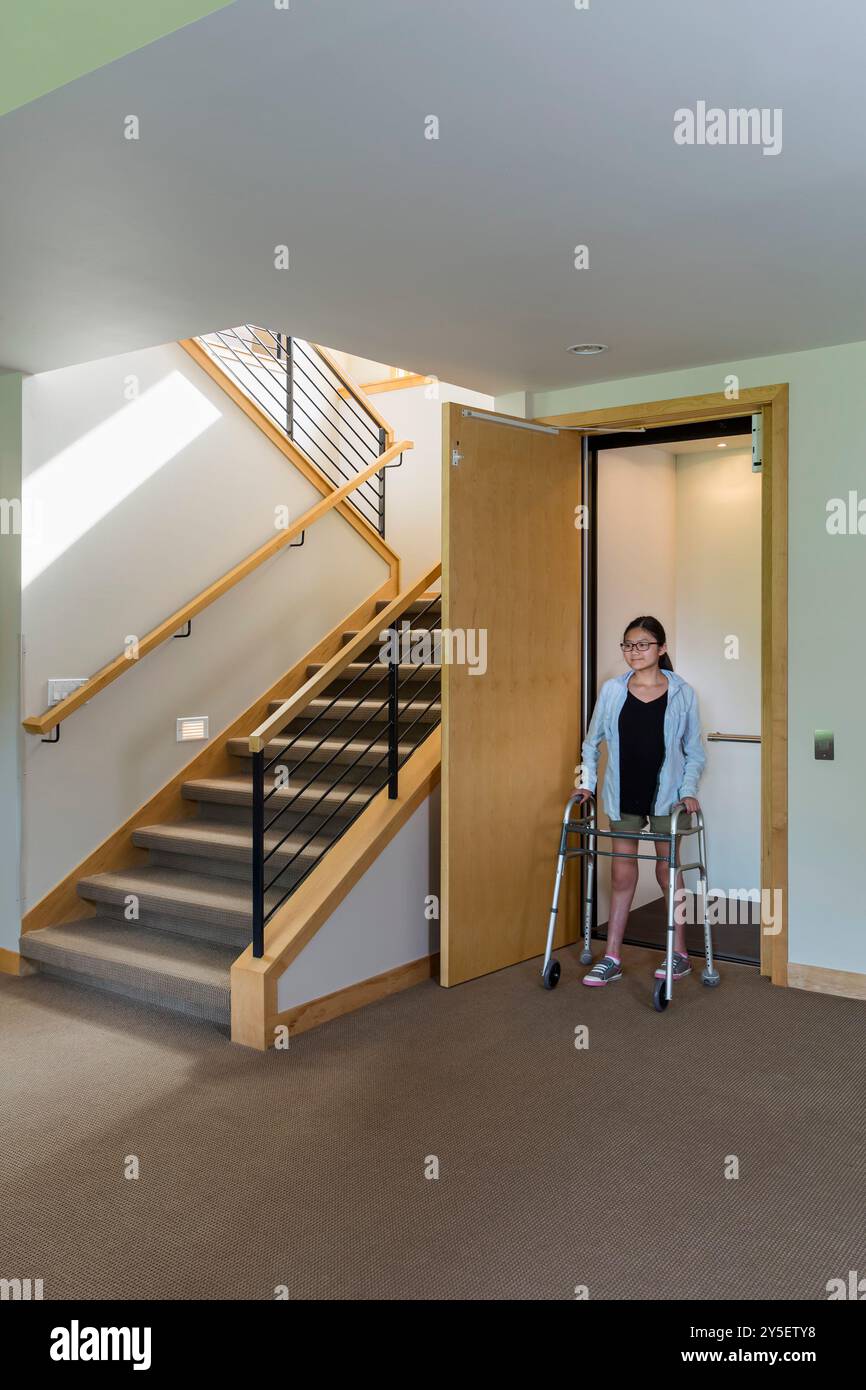 Handicapped girl walks off elevator in lower level of home Stock Photo ...