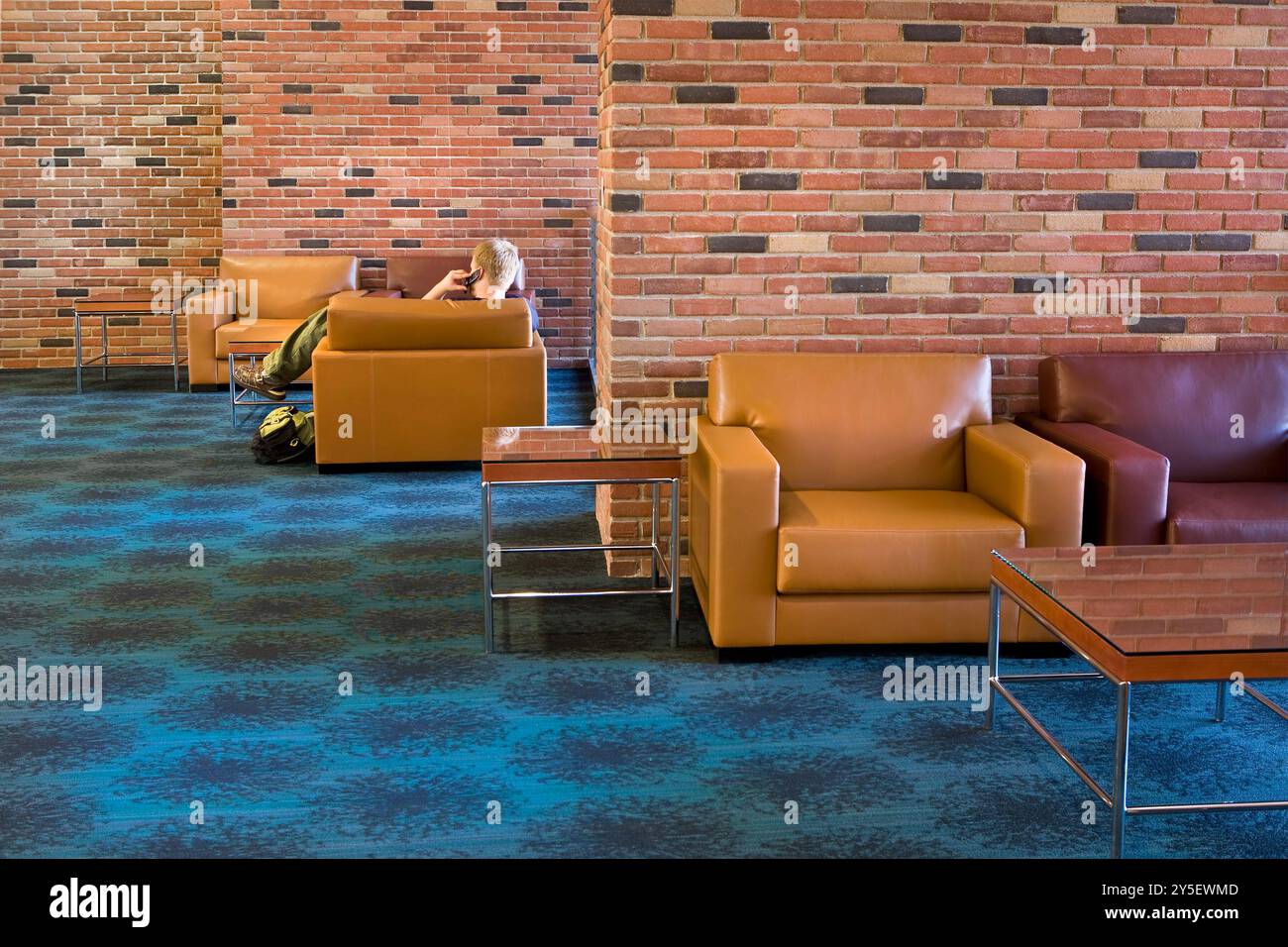 Lounge area with leather chairs and student sitting talking on phone ...