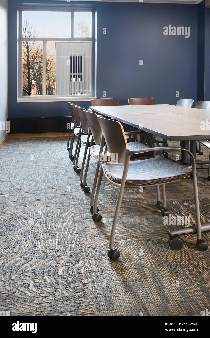 Classroom with chairs lined up at table with blue wall and window to ...