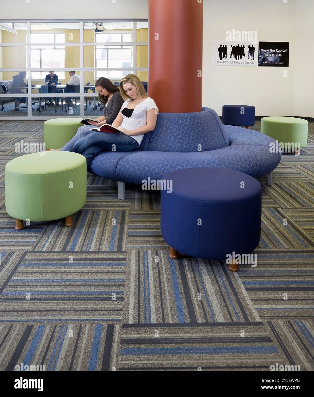 Students sitting in student lounge reading on round sofa Stock Photo ...