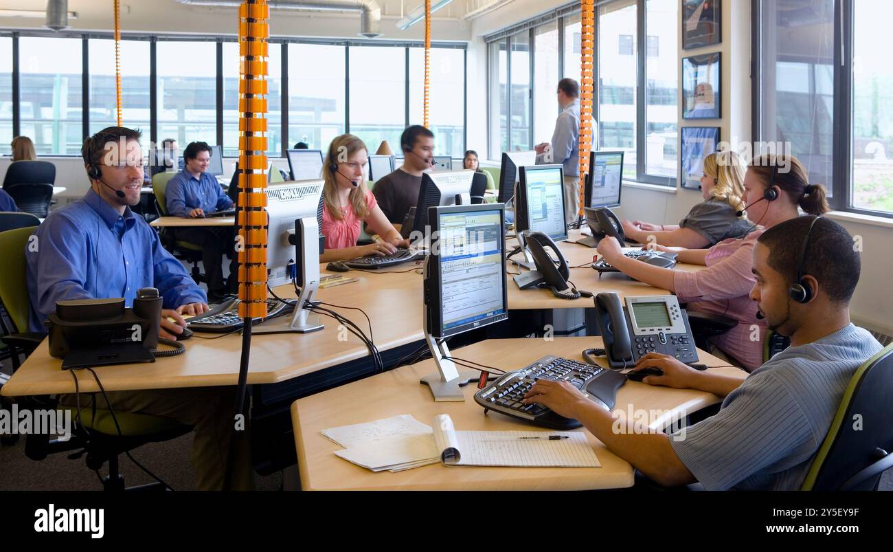 Office with many employees using headsets and sitting in front of ...