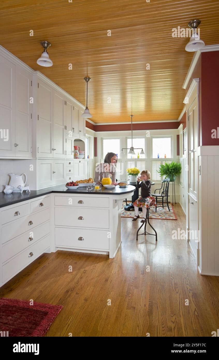 Bright, sunny white kitchen with mother and daughter enjoying breakfast ...