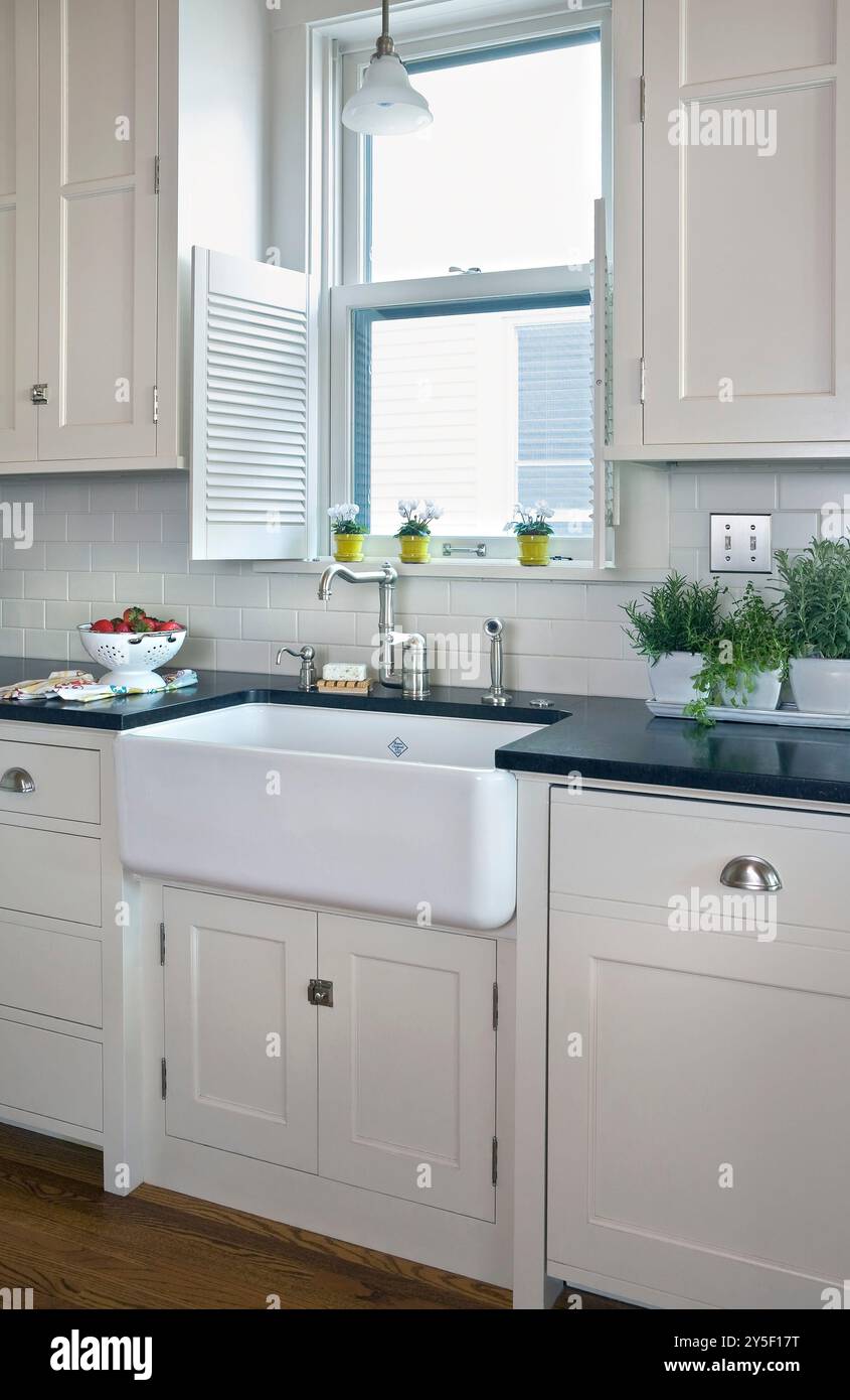 Sink area of white kitchen showing farmhouse style sink Stock Photo - Alamy