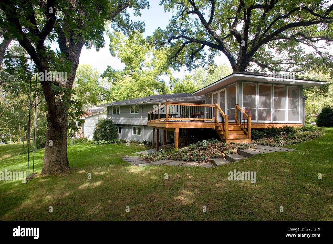Screened porch and deck on house seen from slight angle with tree swing ...