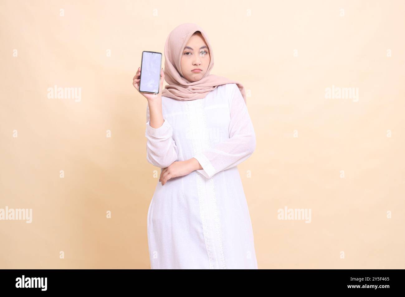 Portrait of an Muslim woman indonesia wearing a hijab, sullenly holding ...