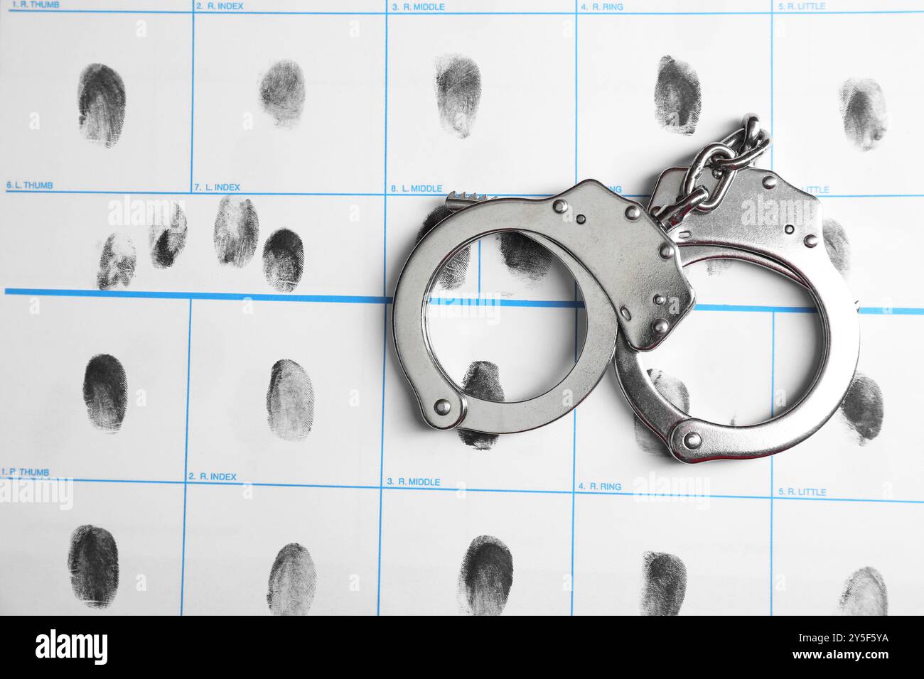 Human fingerprints and handcuffs on paper, top view. Criminal ...