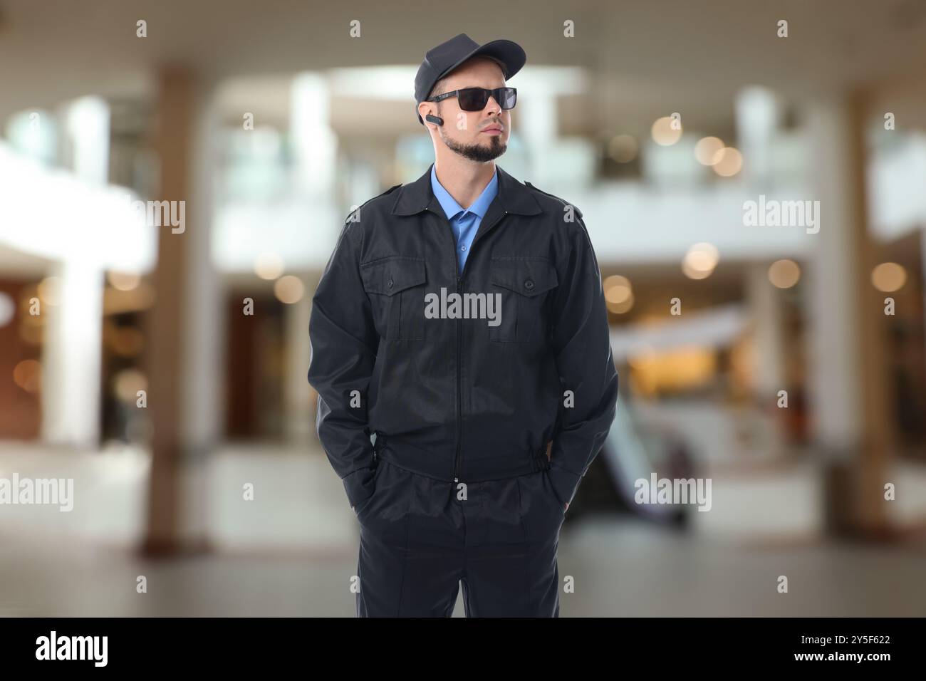 Serious security guard with earpiece in shopping mall Stock Photo - Alamy