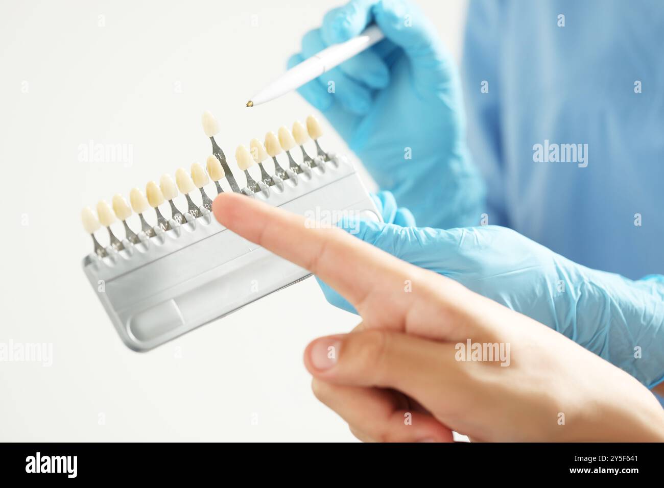Doctor and patient choosing shade on teeth color palette in clinic ...