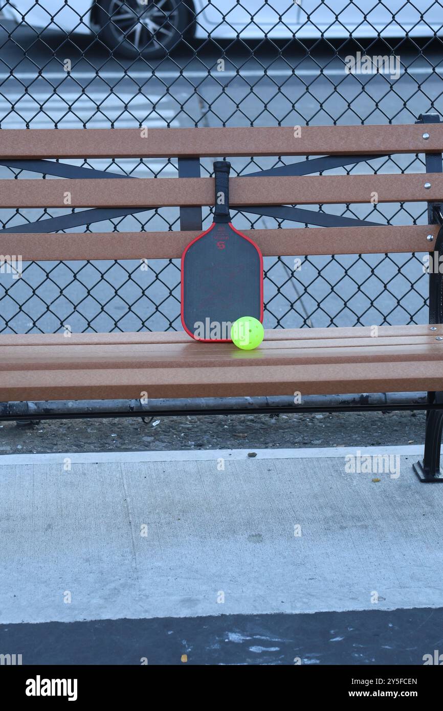 Pickleball paddle and Pickleball on bench near Pickleball court in New ...