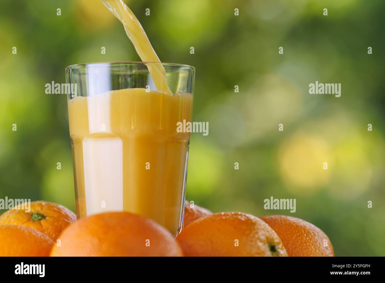 orange juice pouring in glass and ripe fruits near Stock Photo - Alamy