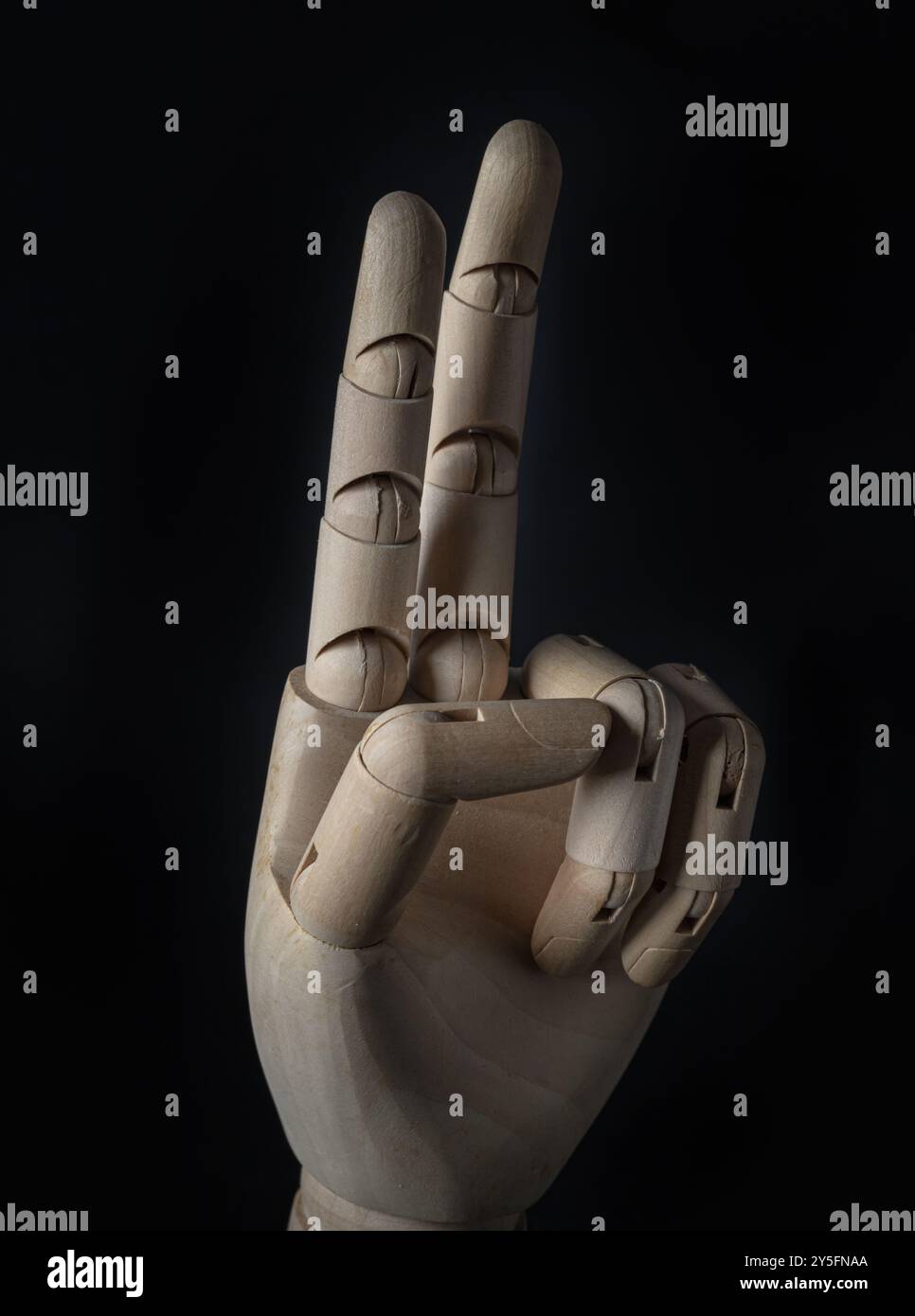 Wooden hand of mannequin with raises two fingers on dark background ...