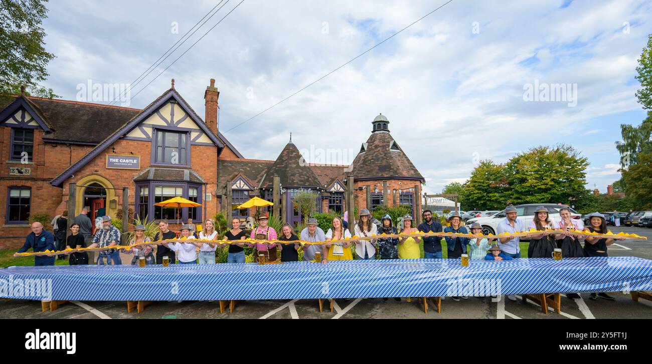 EDITORIAL USE ONLY A group of pub goers hold up a 12.12m long bratwurst ...
