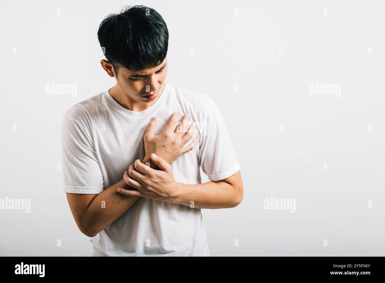 Portrait Asian young man holding his arms around his chest suffering ...