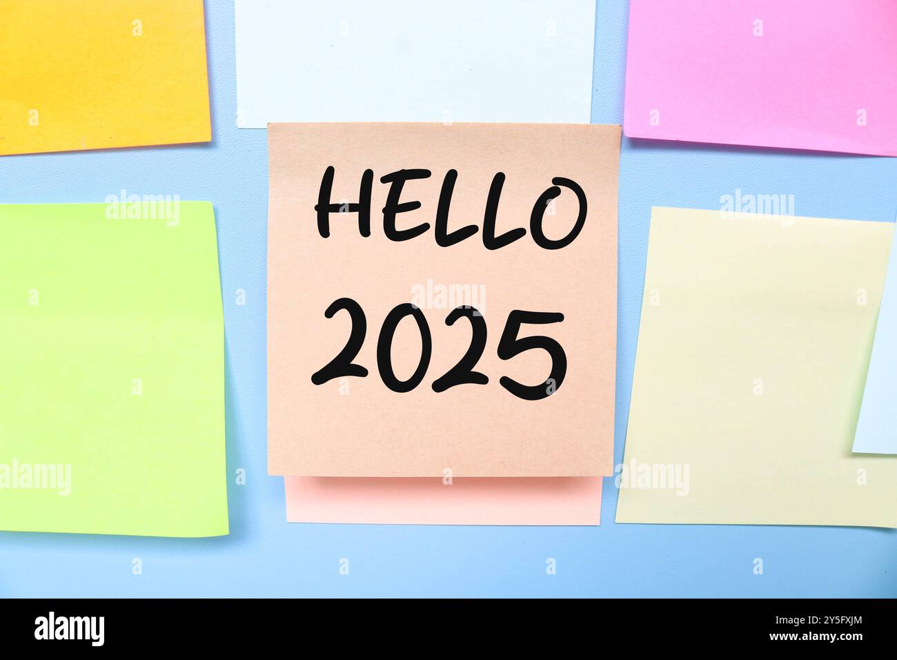 Hello 2025 written on sticky note attached to the wall isolated on blue ...