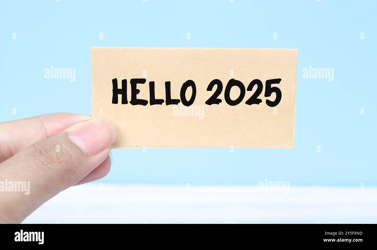 Hand holding note Hello 2025 isolated blue background. New year concept ...