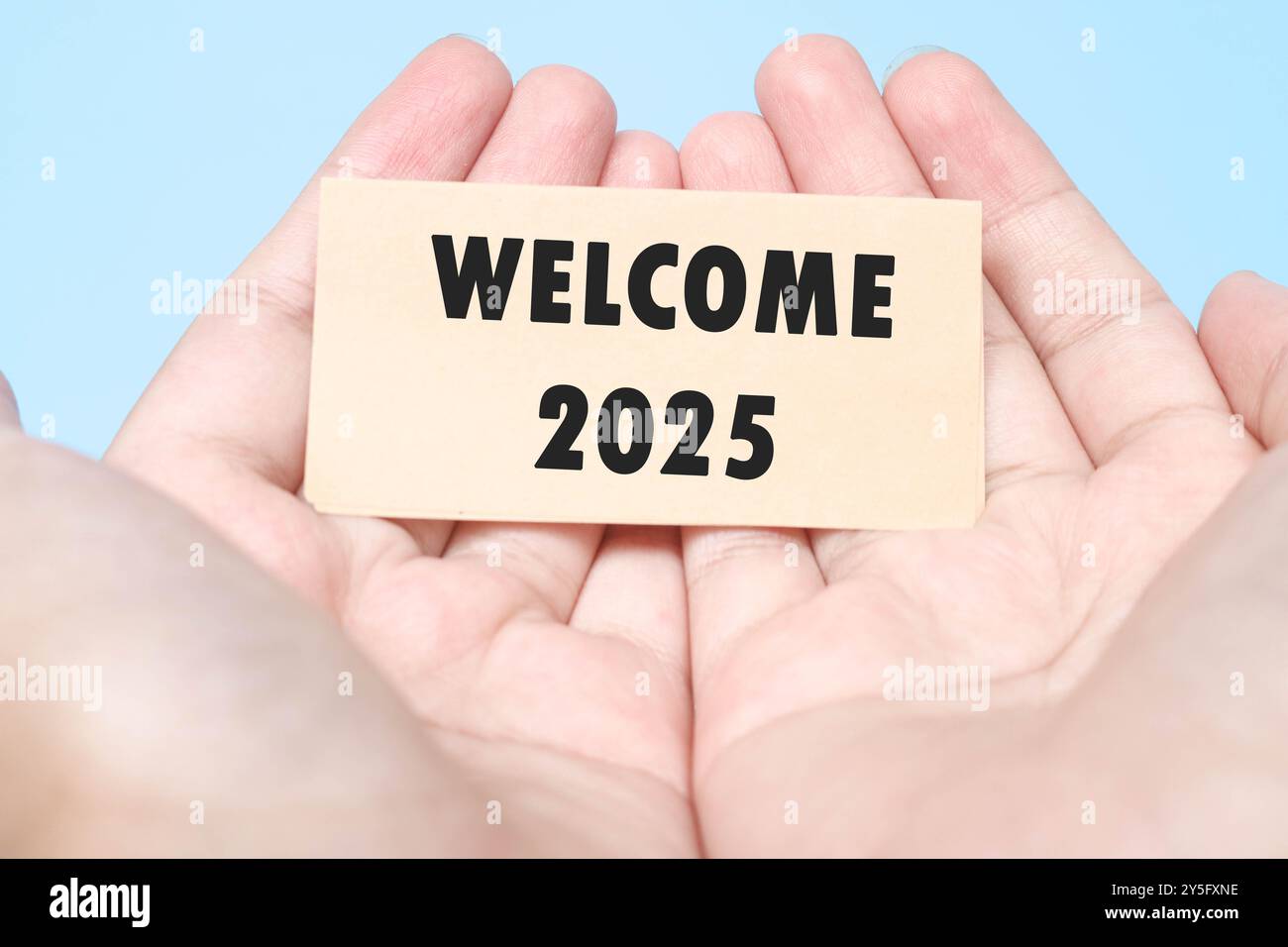 Hand holding a note Welcome 2025 with a blue background. New year ...