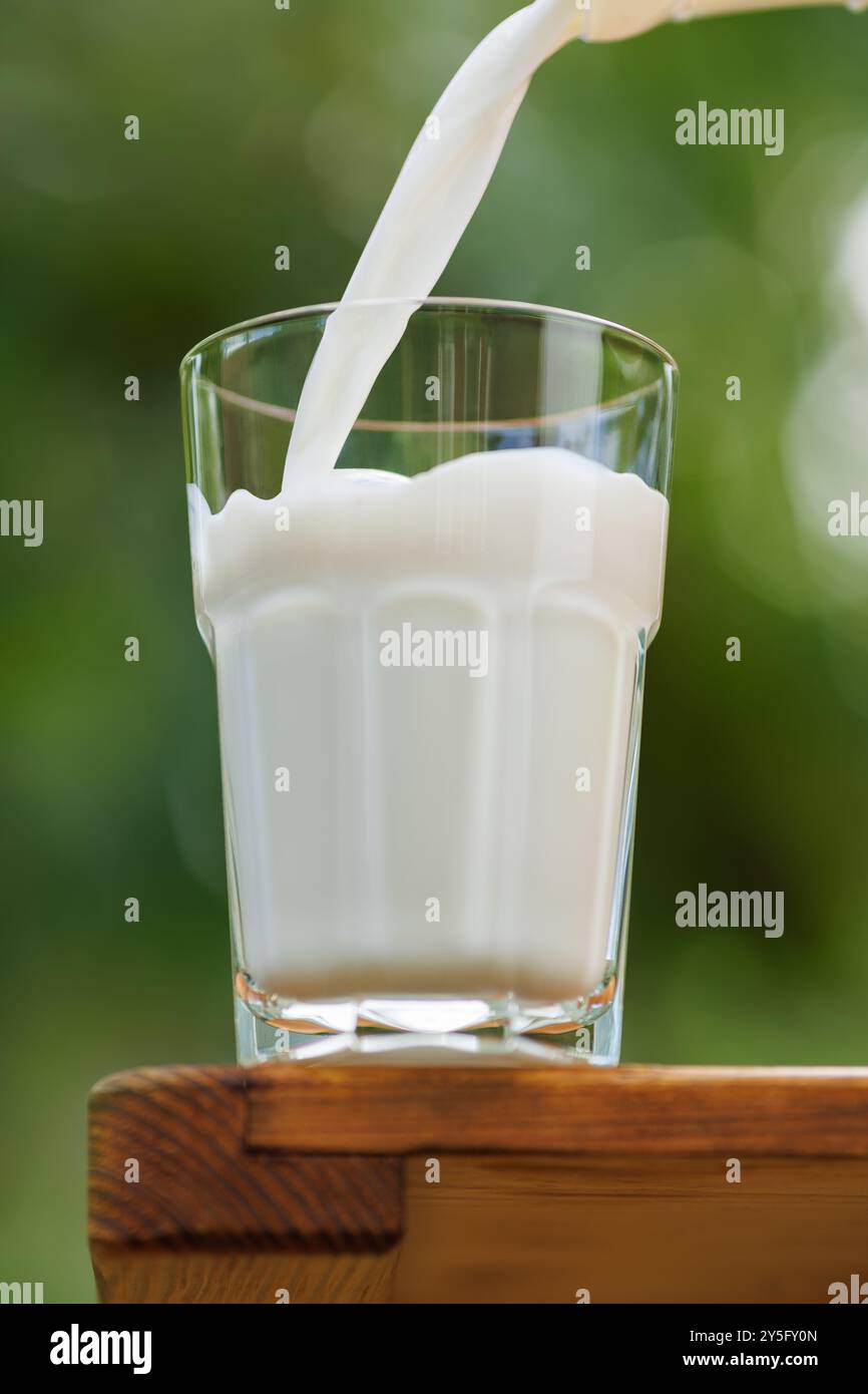 milk pouring into glass on table edge outdoors Stock Photo - Alamy