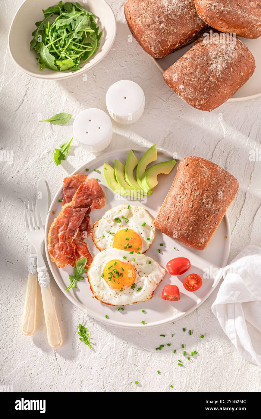 British breakfast with egg, tomato and rolls. Bun with eggs and bacon ...
