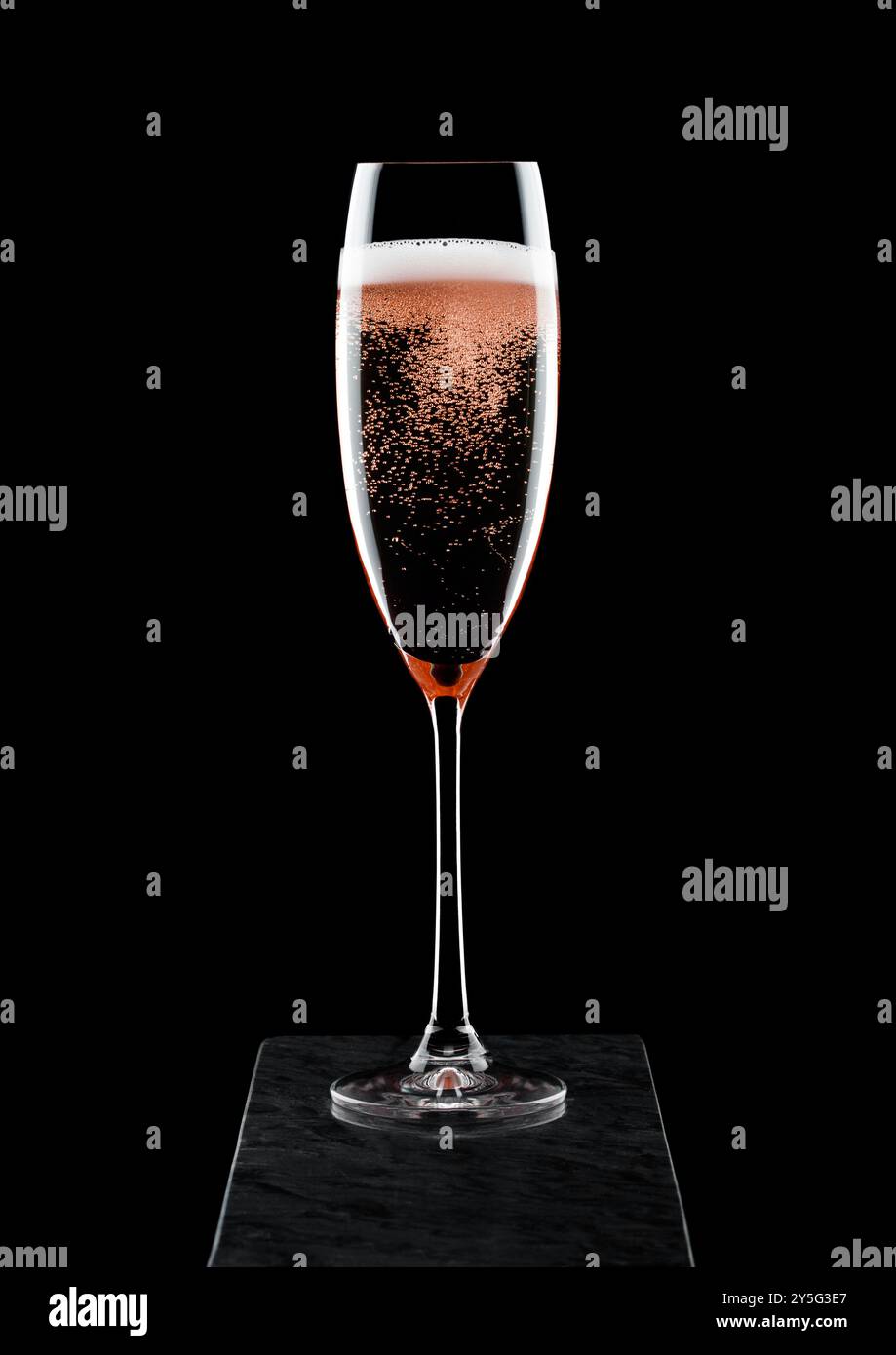 Elegant glass of pink rose champagne with bubbles on black marble board ...