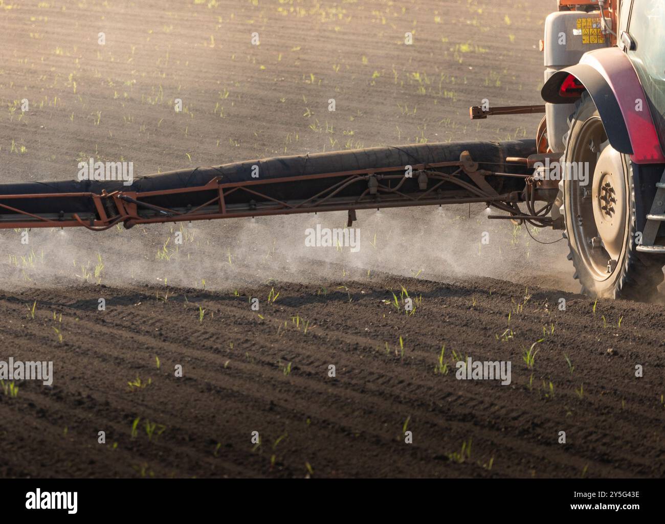 Tractor spraying pesticides on field with sprayer Stock Photo - Alamy