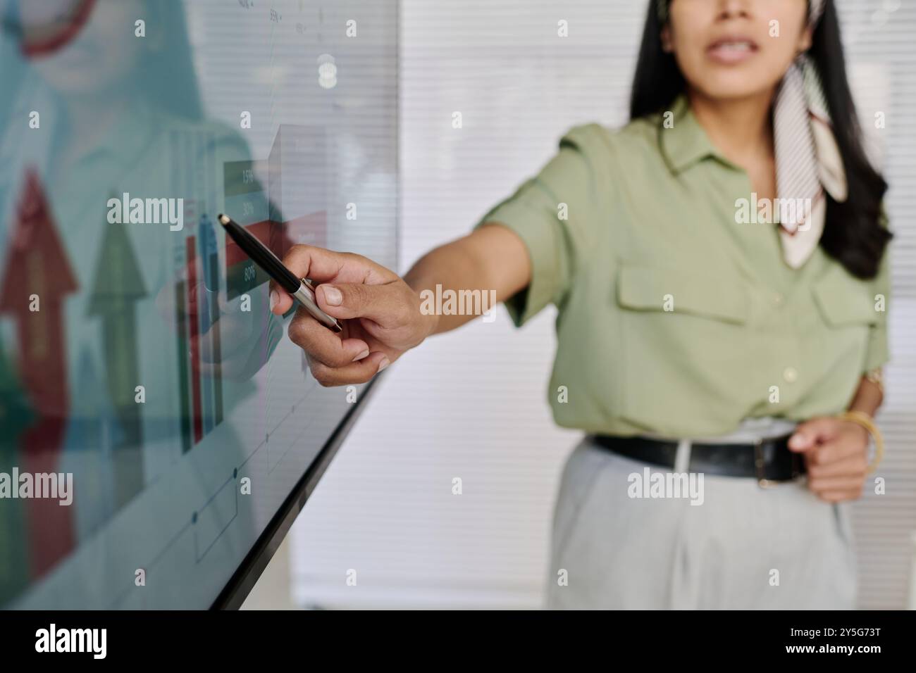 Woman pointing at data on interactive display during presentation in ...
