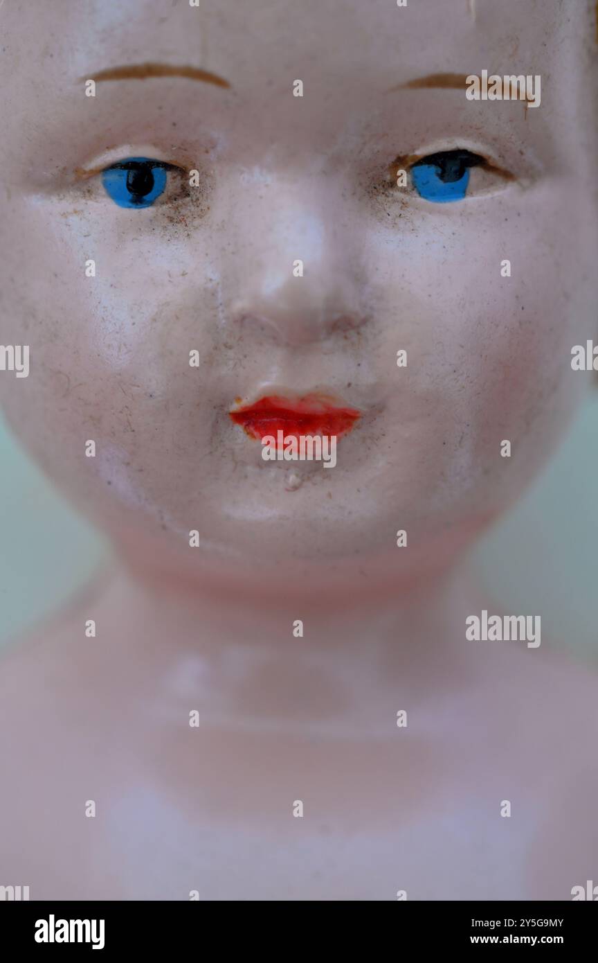 Detail of face of 1950s girl doll with bright blue eyes red lips and ...