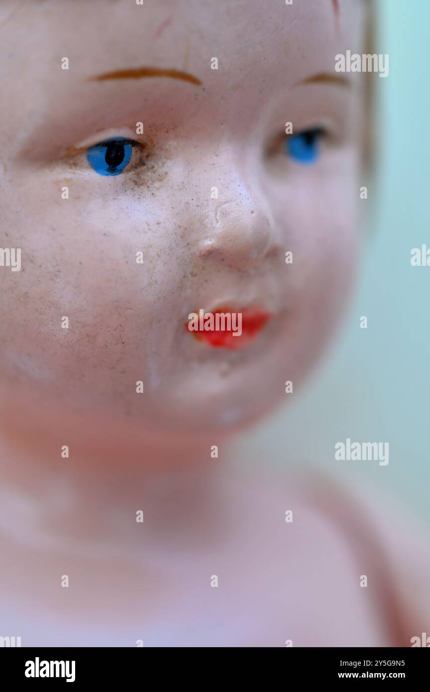 Detail of face of 1950s girl doll with bright blue eyes red lips and ...