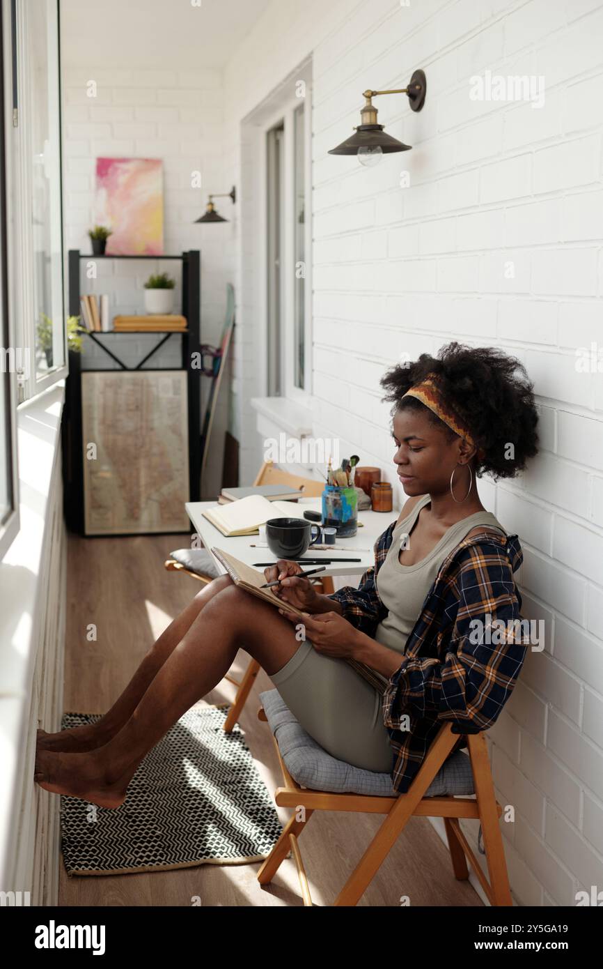 Woman focusing on her writing seated in a bright, modern workspace with ...