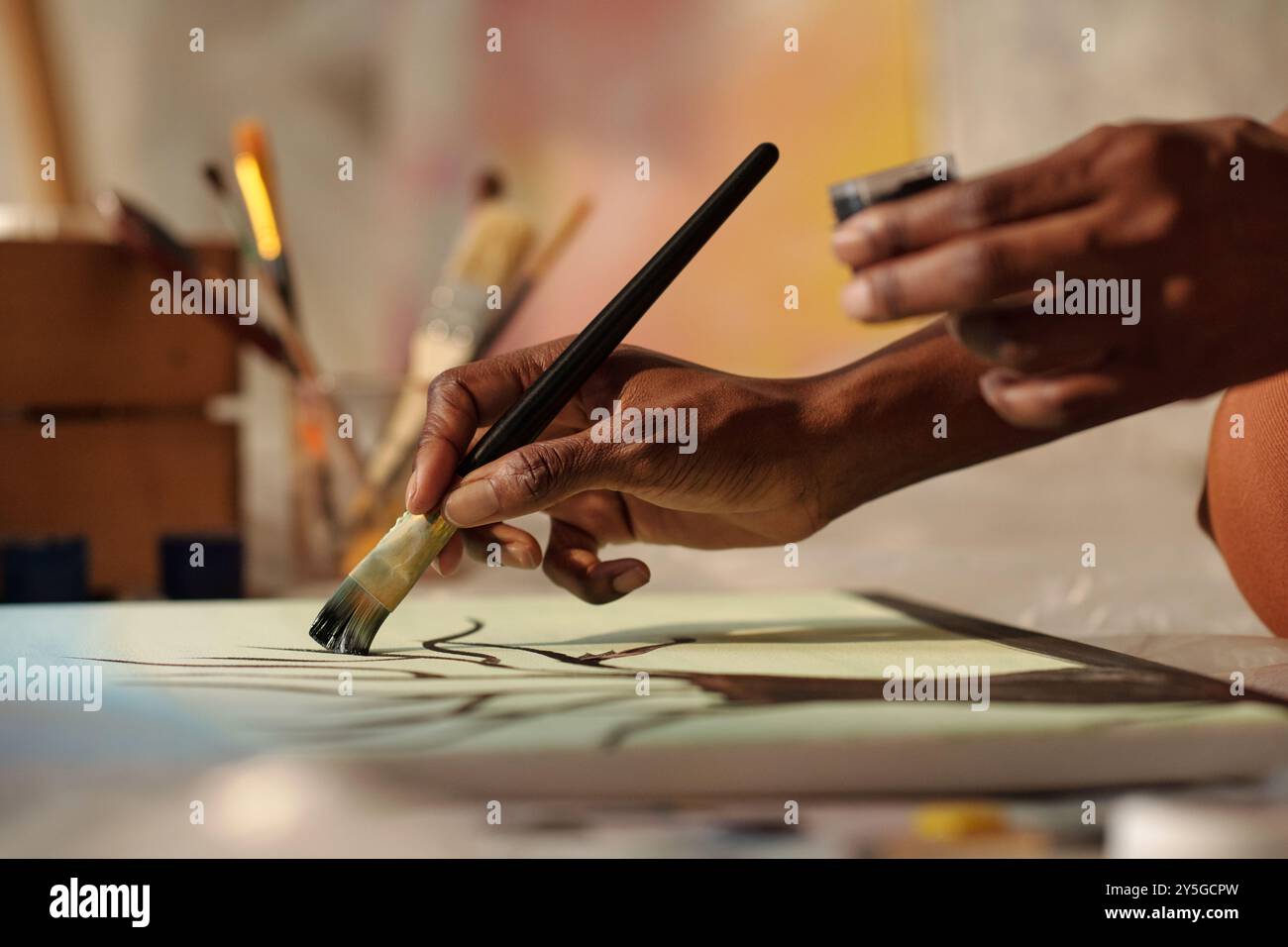 Close-up view of artist's hand holding paintbrush while painting on ...
