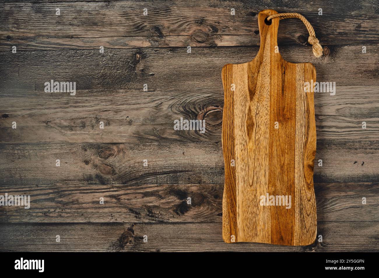A handcrafted wooden cutting board rests on a weathered wooden table ...