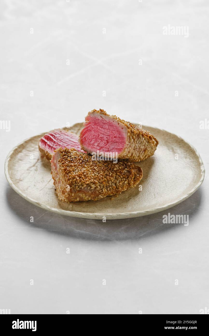 On a simple plate, tuna slices coated in sesame seeds showcase a ...