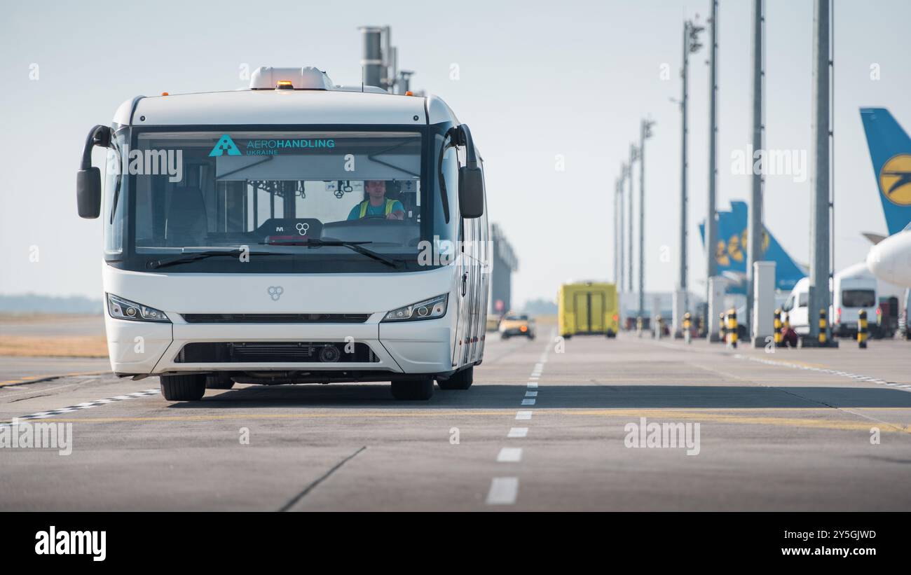 Apron bus driving towards camera. Perspective view of airport service ...