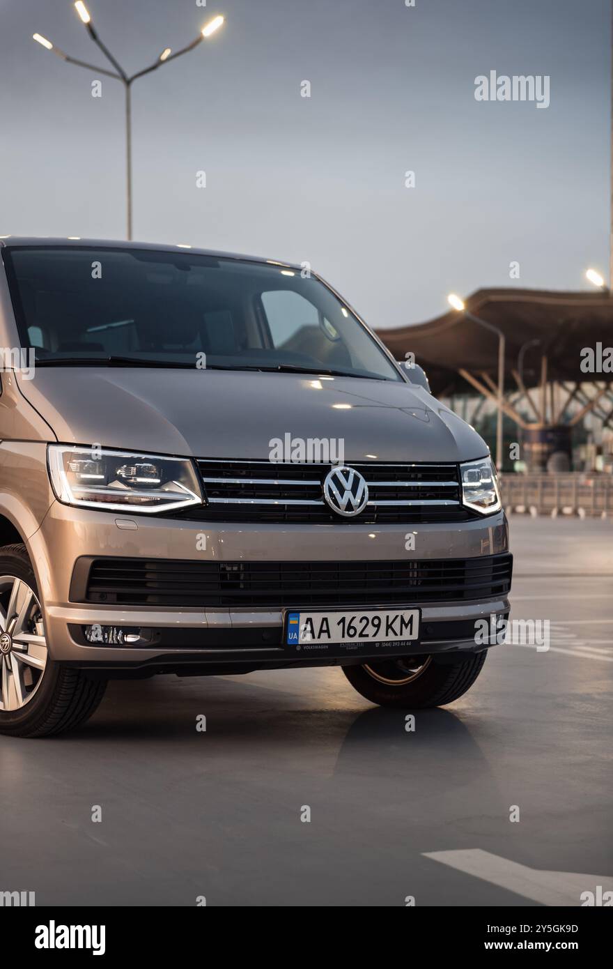 Beige VW Transporter on top level of parking garage. Front end view of ...