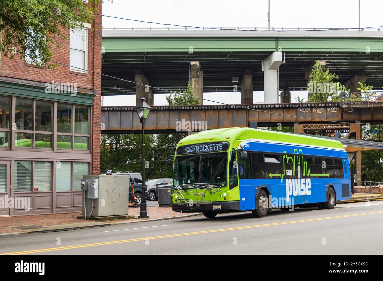 A green and blue bus is driving down a street. The bus is labeled with ...