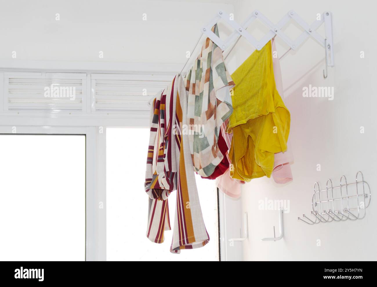 Wet clothes hanging on a clothes rail in a small apartment laundry room ...