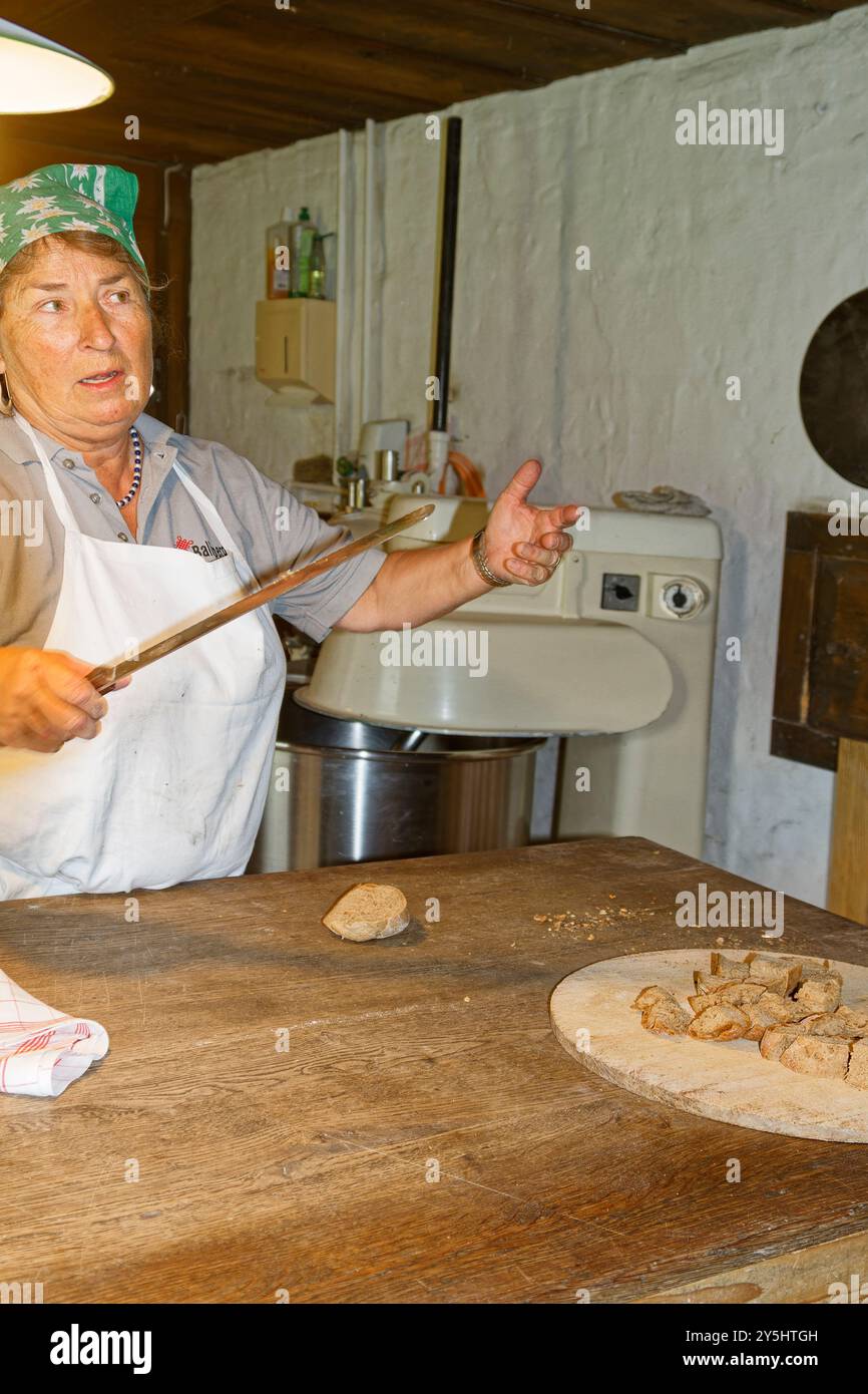 baking bread, woman describing task, large mixer, wood tray with bread ...