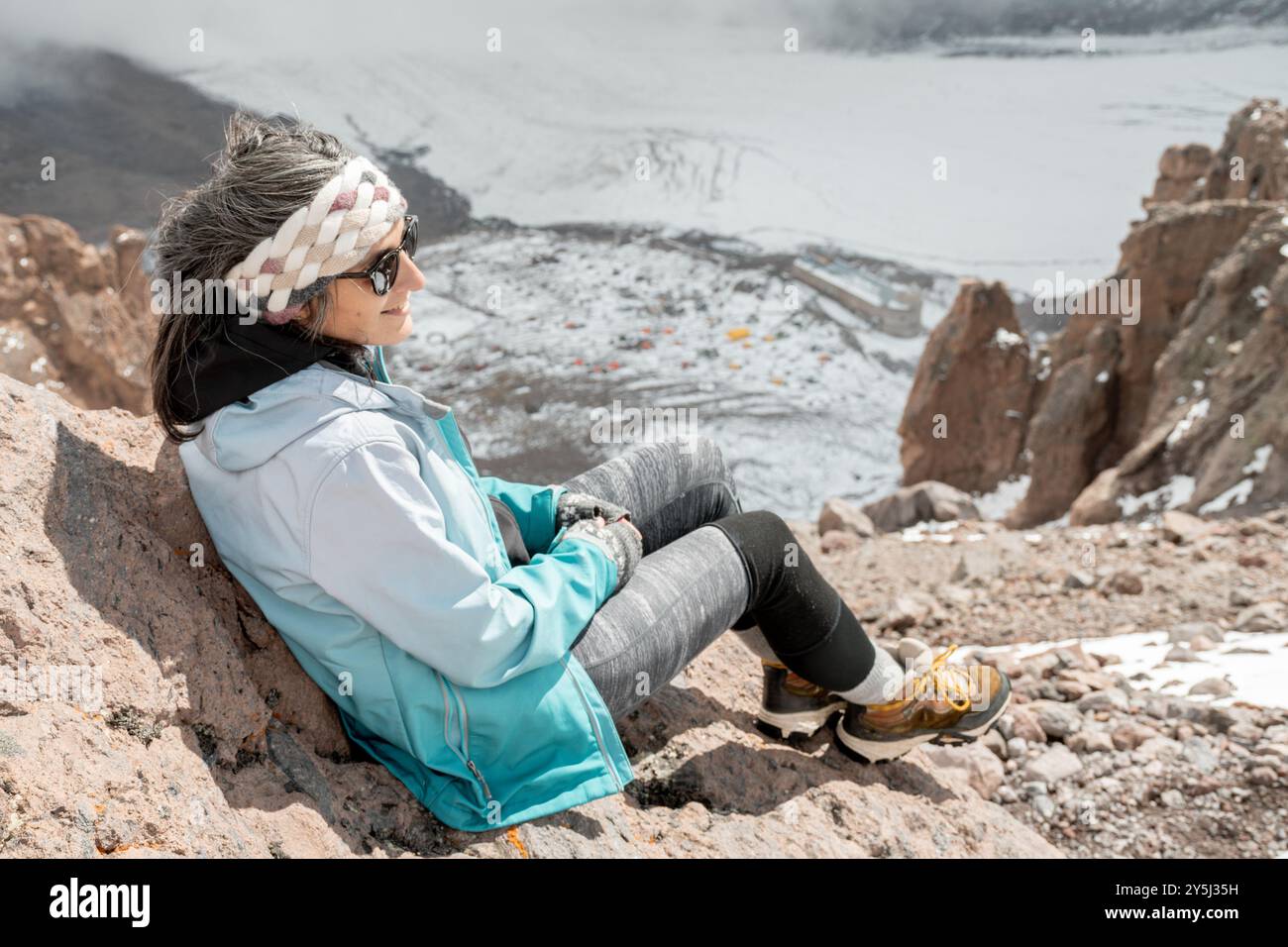 Woman climber sit over Bethlemi hut meteo station and Mount Kazbek base ...