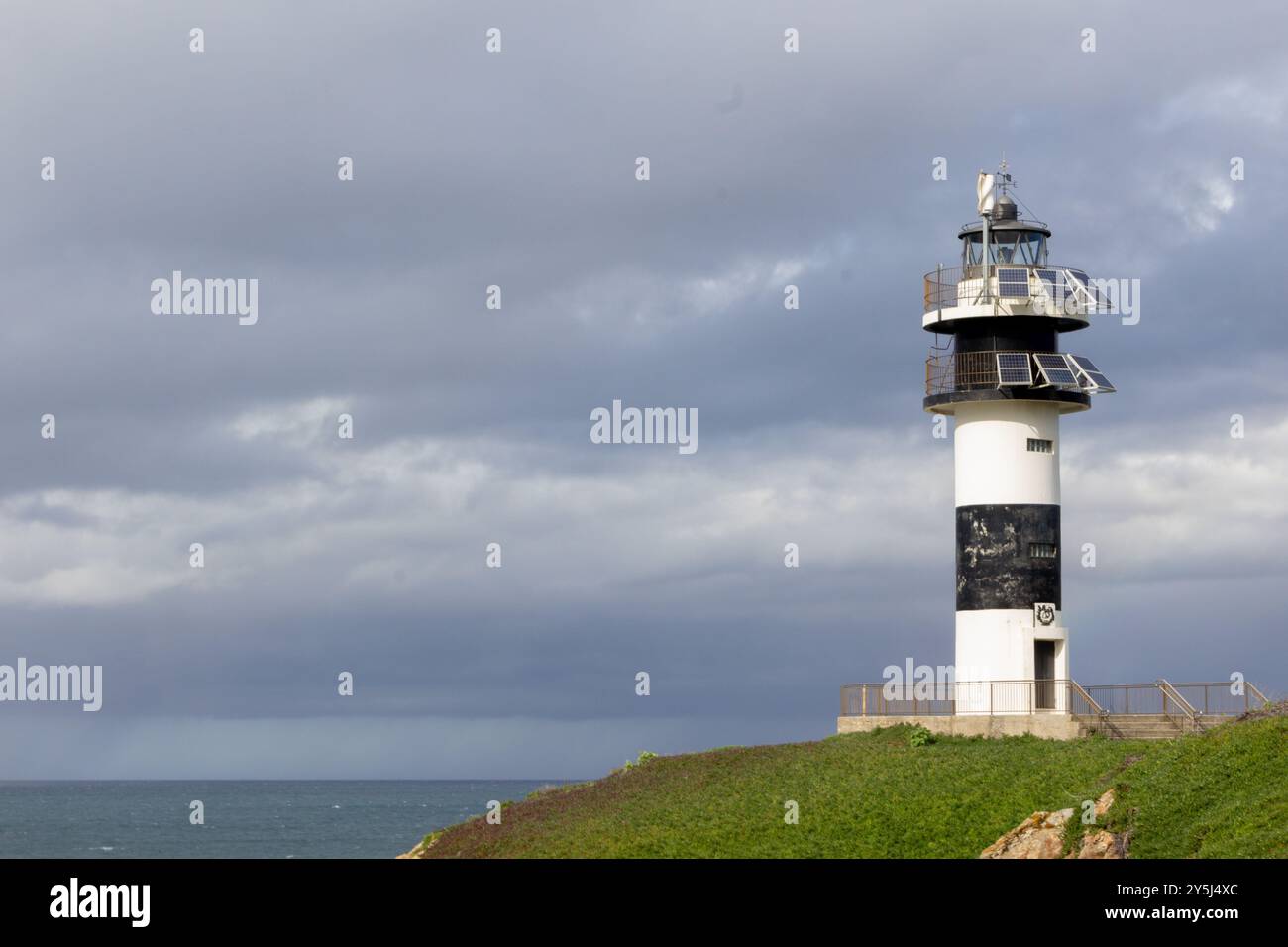 Coastal landmark: Lighthouse by sea with cloudy sky, striped base ...