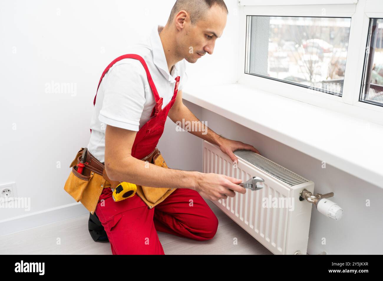 Professional plumber installing new heating radiator in room Stock ...