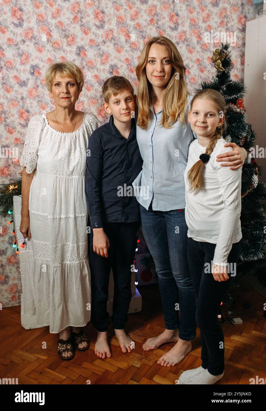 A family stands together, smiling warmly in front of a decorated ...