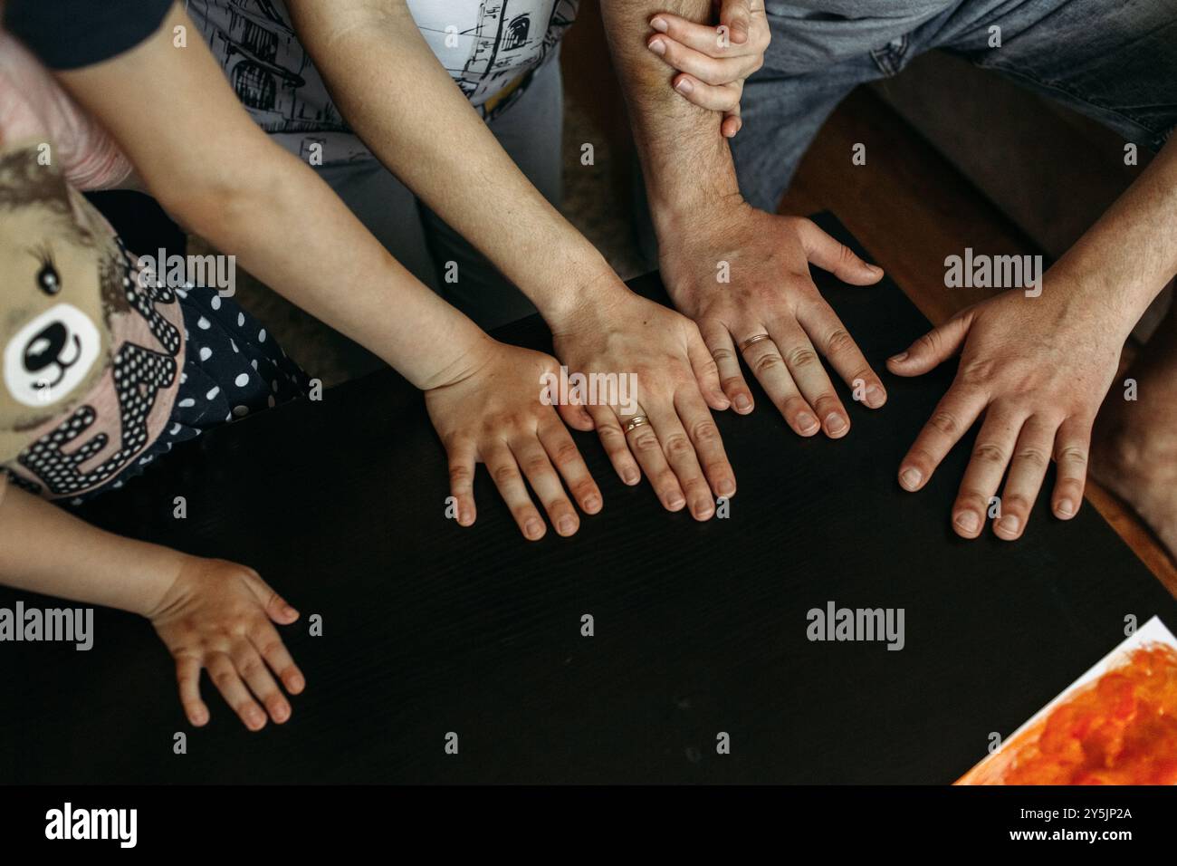 Different-sized hands come together on a table, symbolizing unity and ...