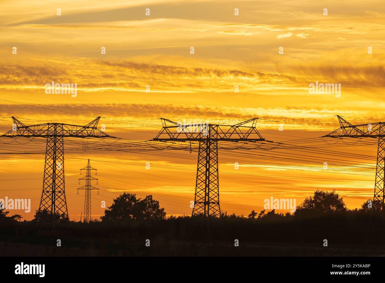 Power pylons of an overhead line at sunset Stock Photo - Alamy